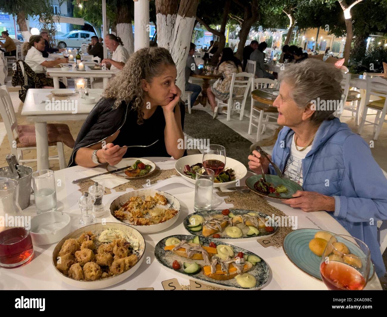 Malia, Crete, Greece. 2022. Two women in a Greek restaurant enjoying a ...