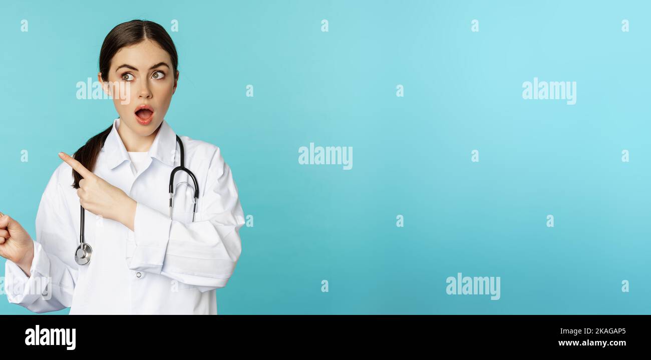 Surprised female doctor, physician with stethoscope, pointing and ...