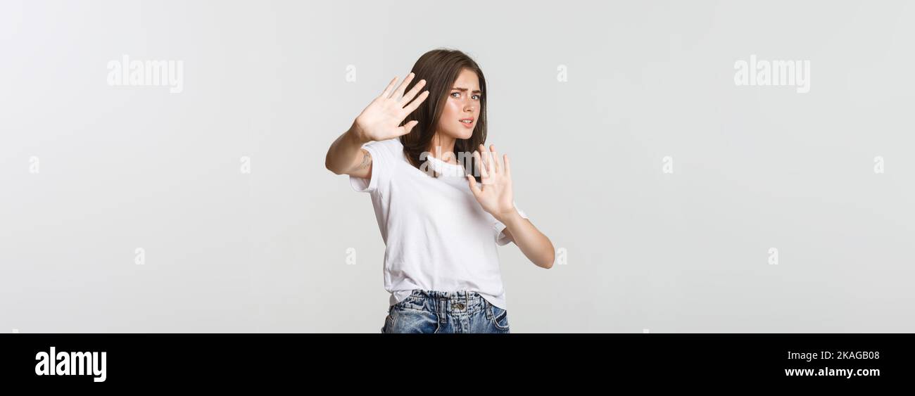 Scared and insecure cute girl raising hands in stop gesture, defending ...