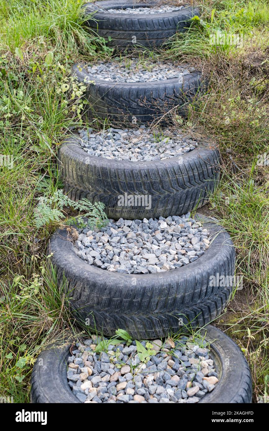 Old used car Tires filled with granite rock stones to make stairs on on ...