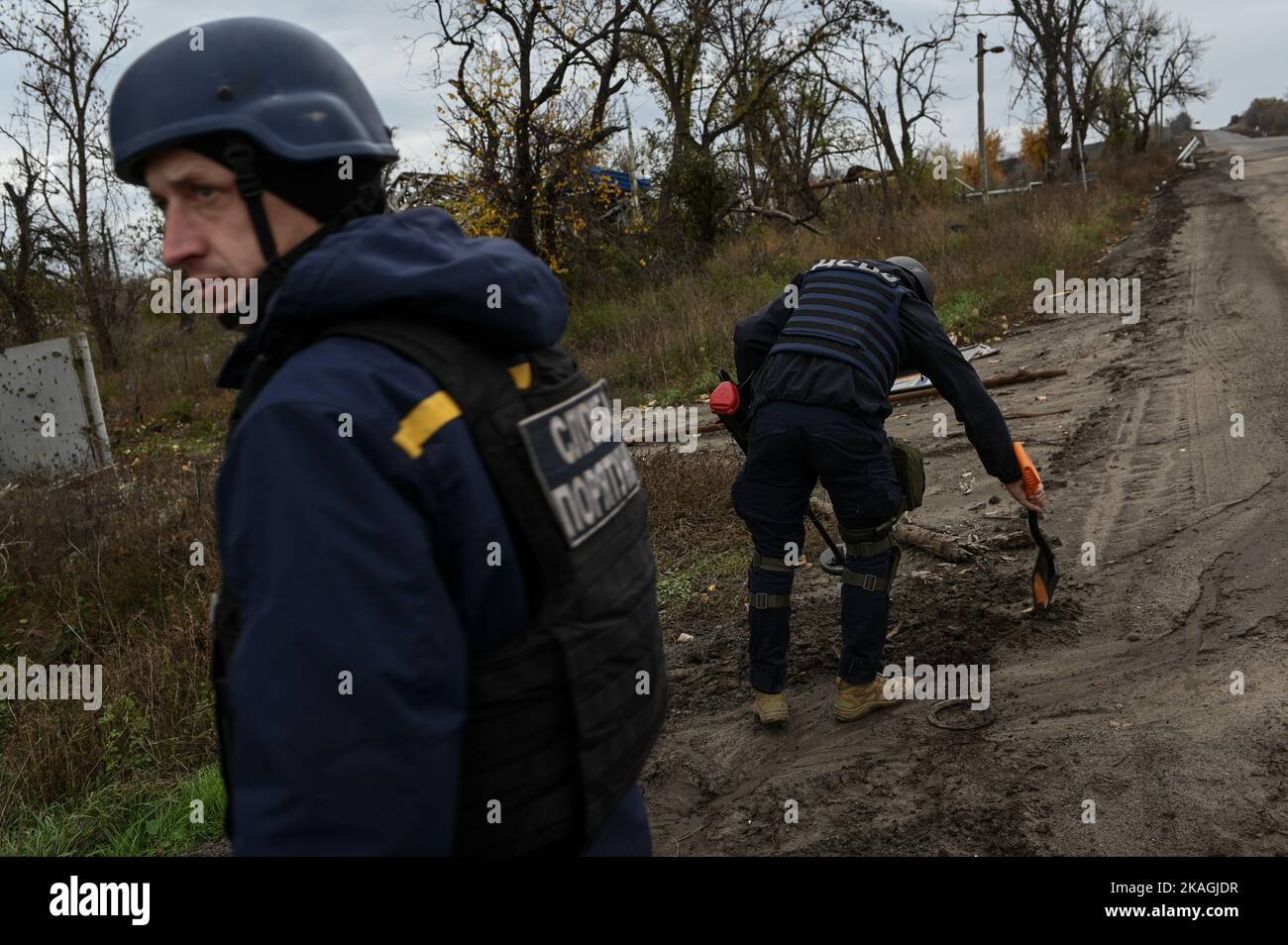 Two Ukrainian bomb technicians check a dirt path for buried explosives ...