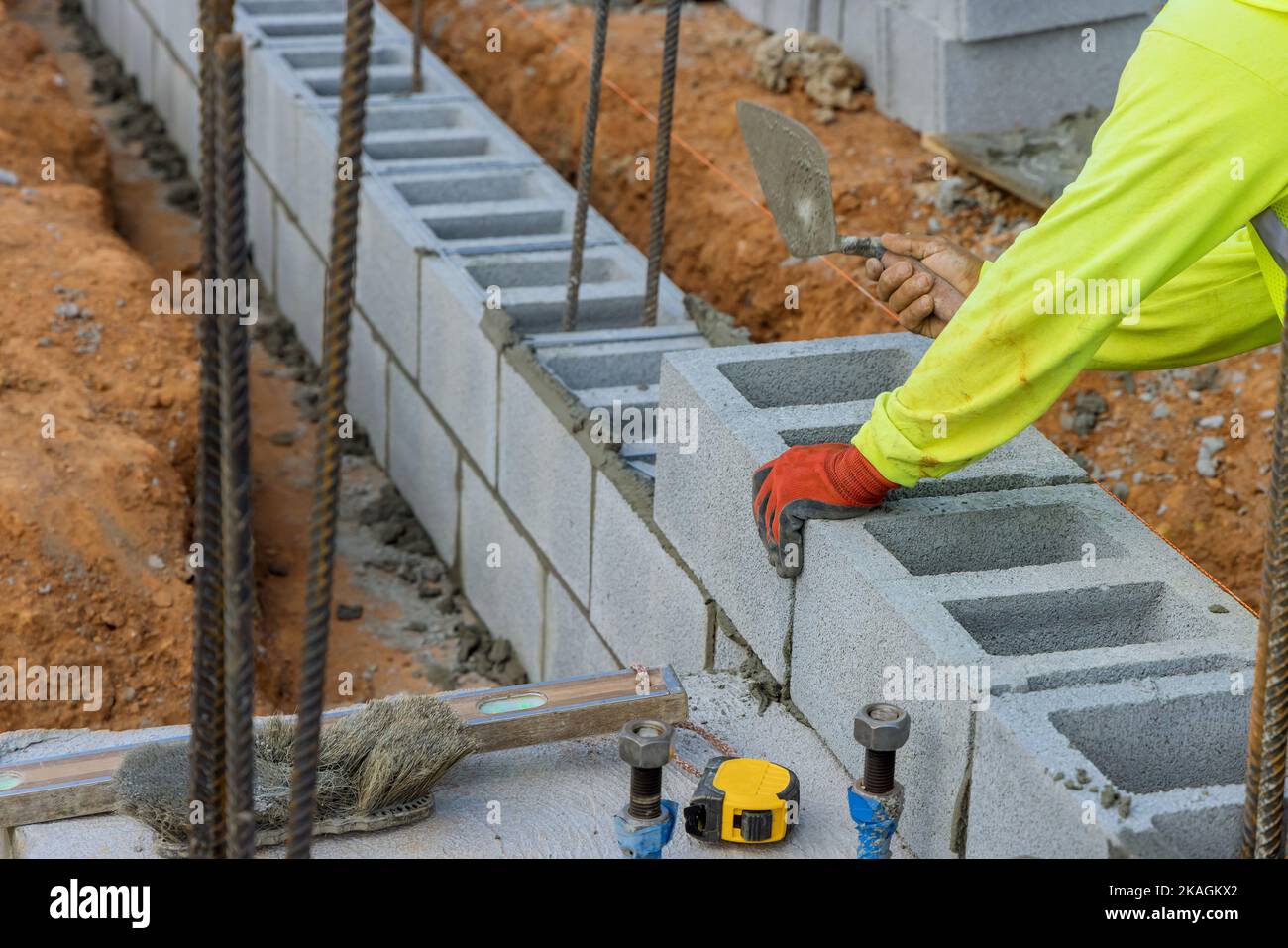 Bricklayer construction worker putting down another row of cement ...