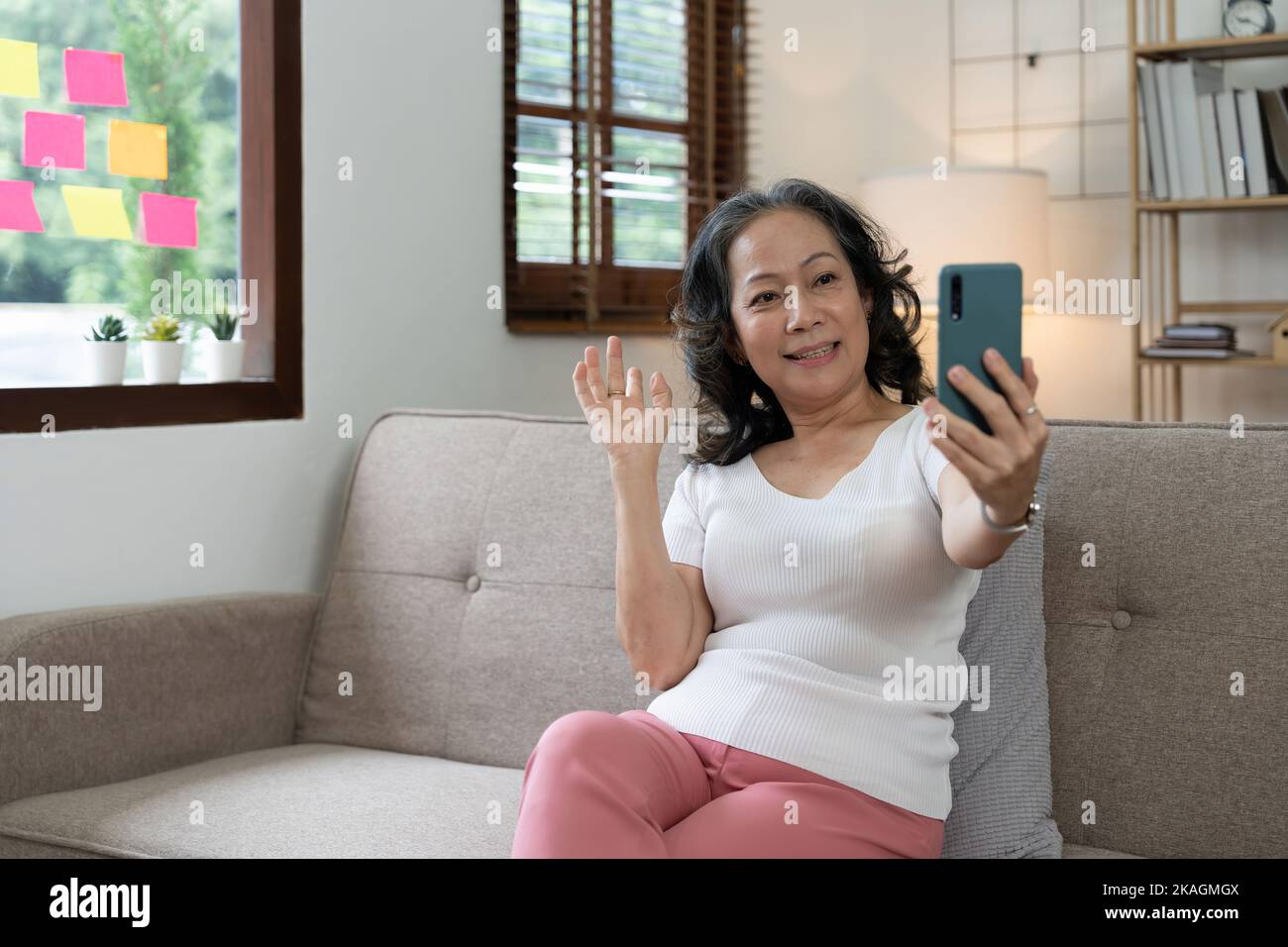 Asian Elderly Woman Taking Selfie On Mobile Phone While Sitting On Sofa