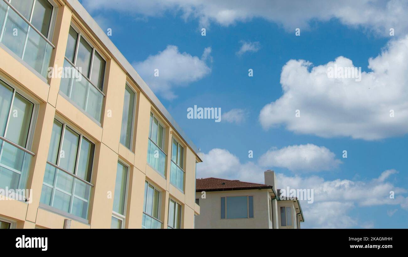 Panorama White puffy clouds Two low rise buildings with glass panels at ...