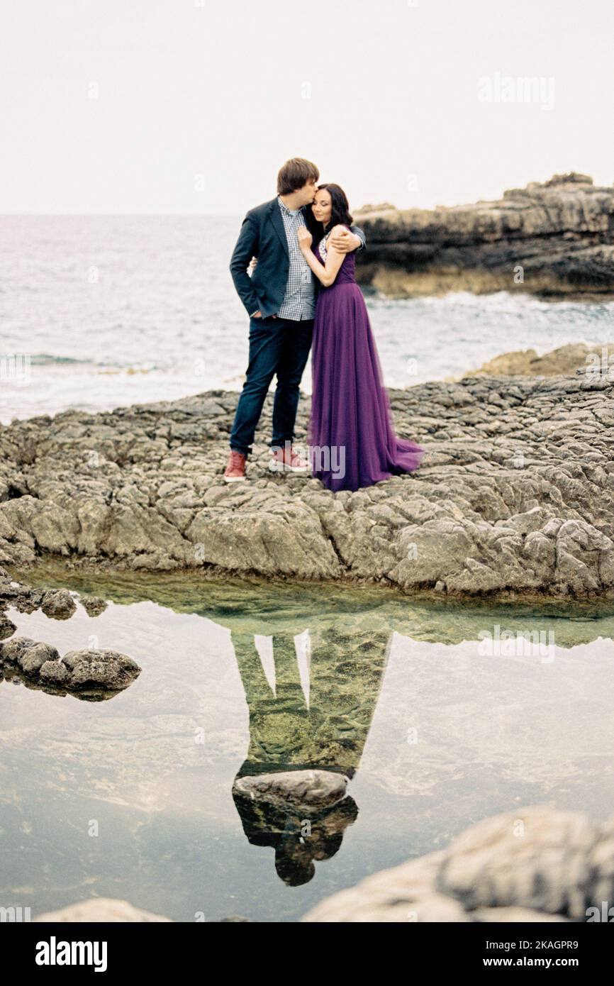 Man hugging a woman on the rocks by the sea Stock Photo - Alamy
