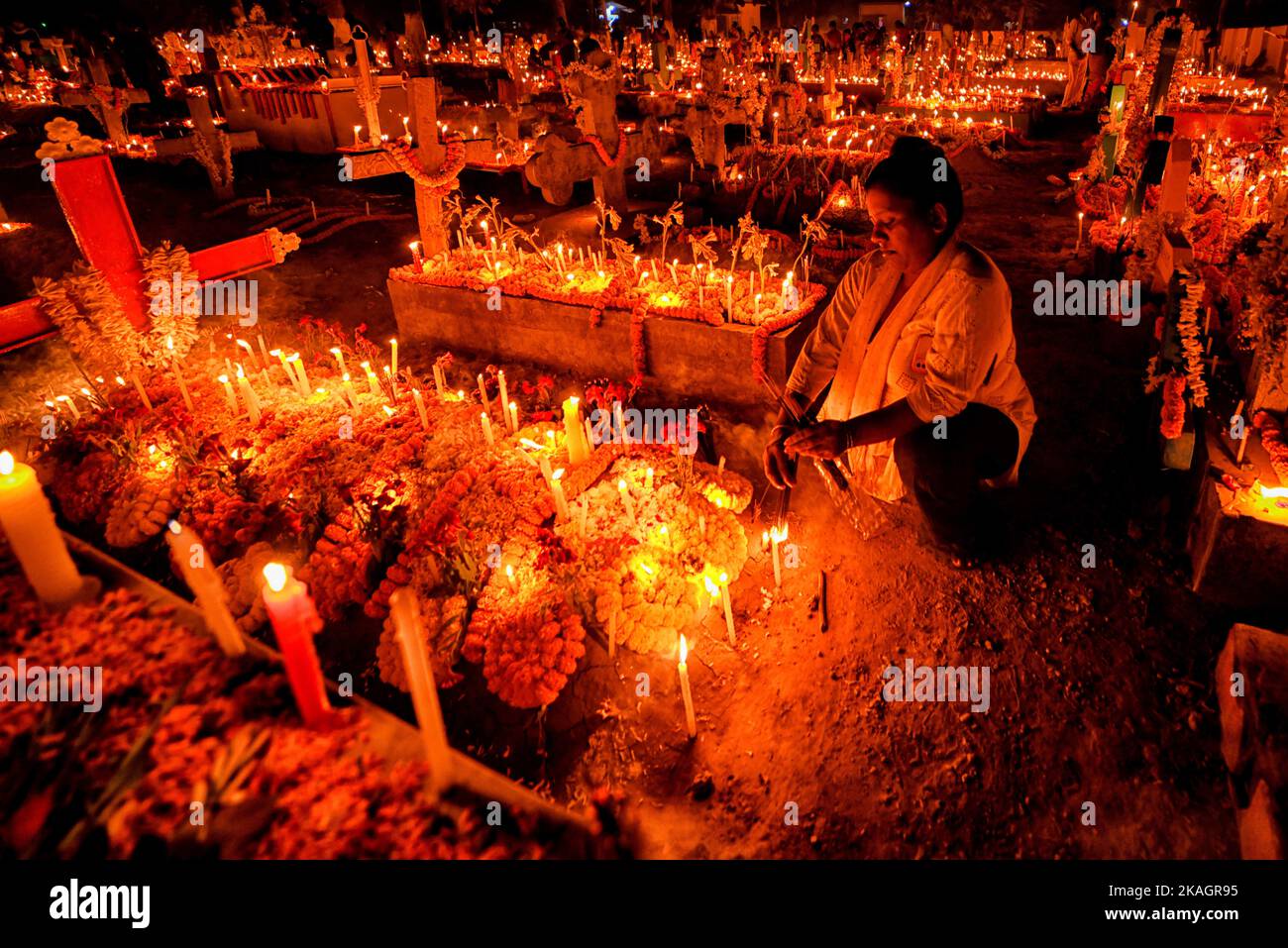 A Christian lady pays respect with lit candles beside the grave of her ...