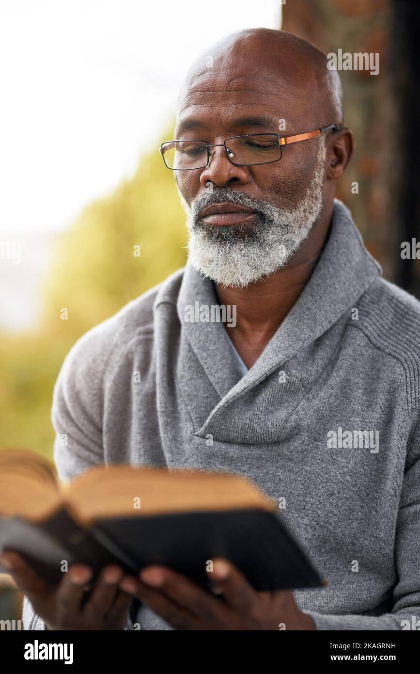 Studying the scriptures. a handsome senior man reading his bible while ... Studying the scriptures. a handsome senior man reading his bible while ...