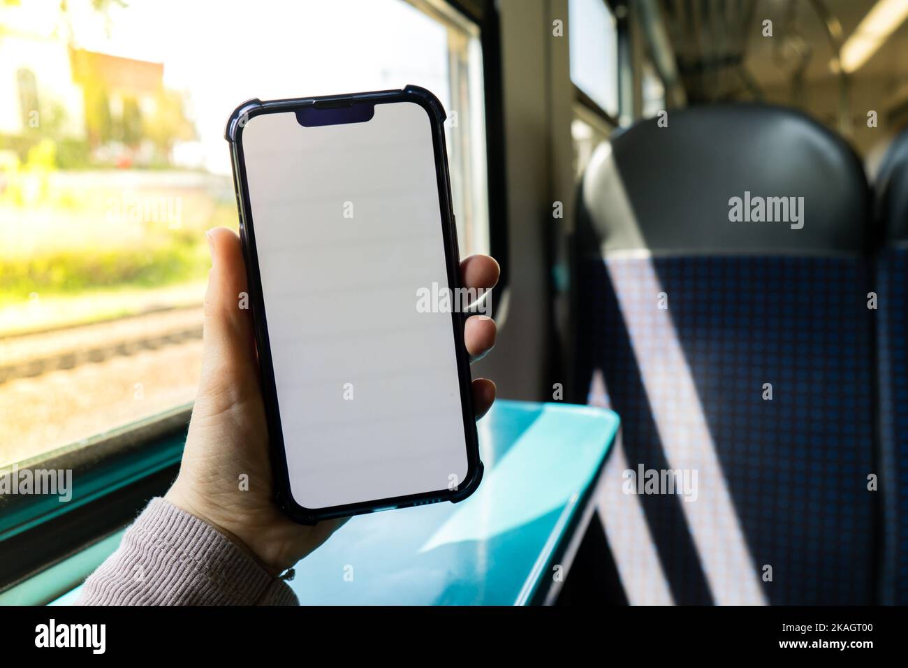 Female hand holding white screen phone in the train. Social Network ...