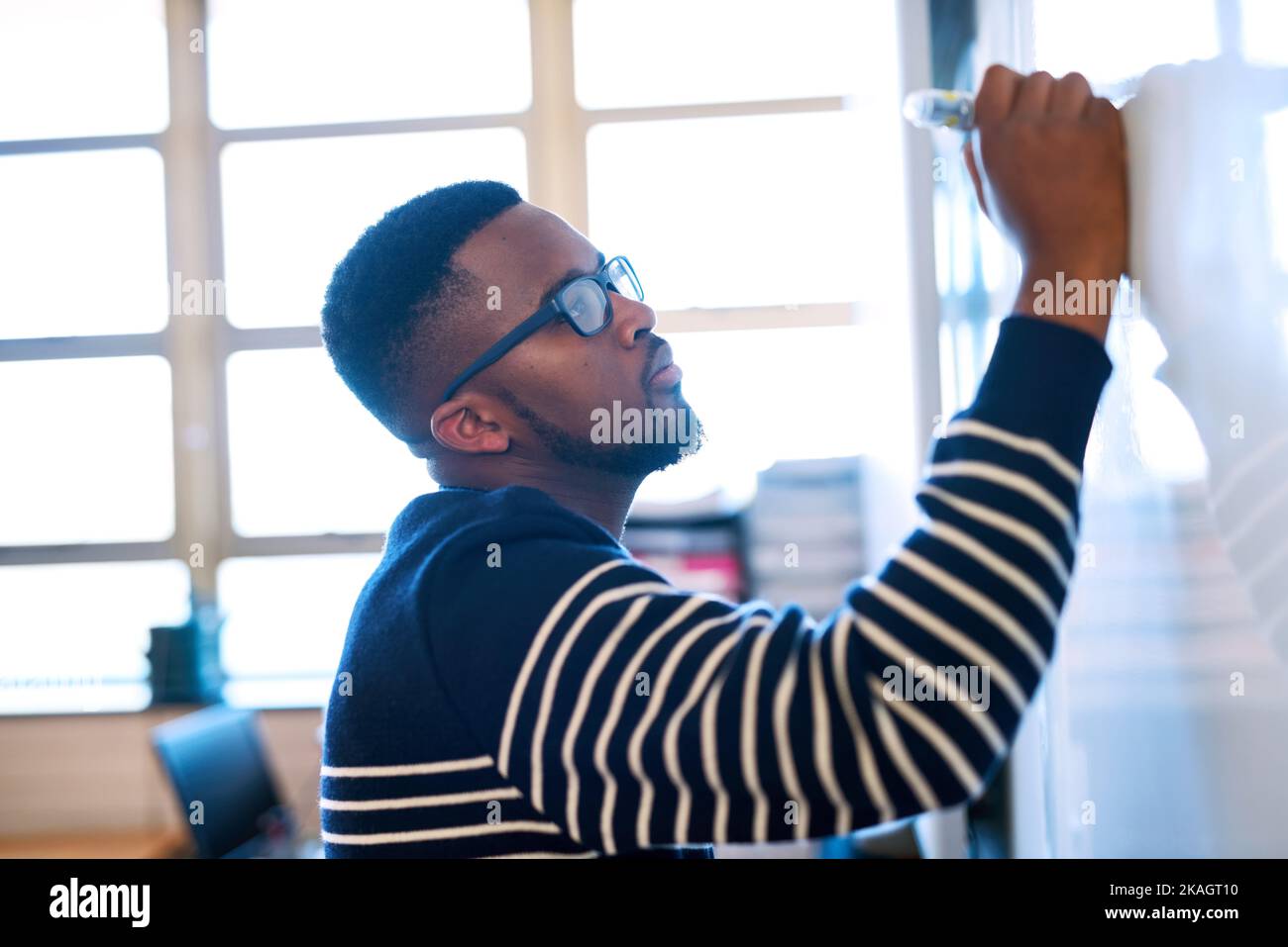 He can solve just about anything. a young man writing on a whiteboard ...