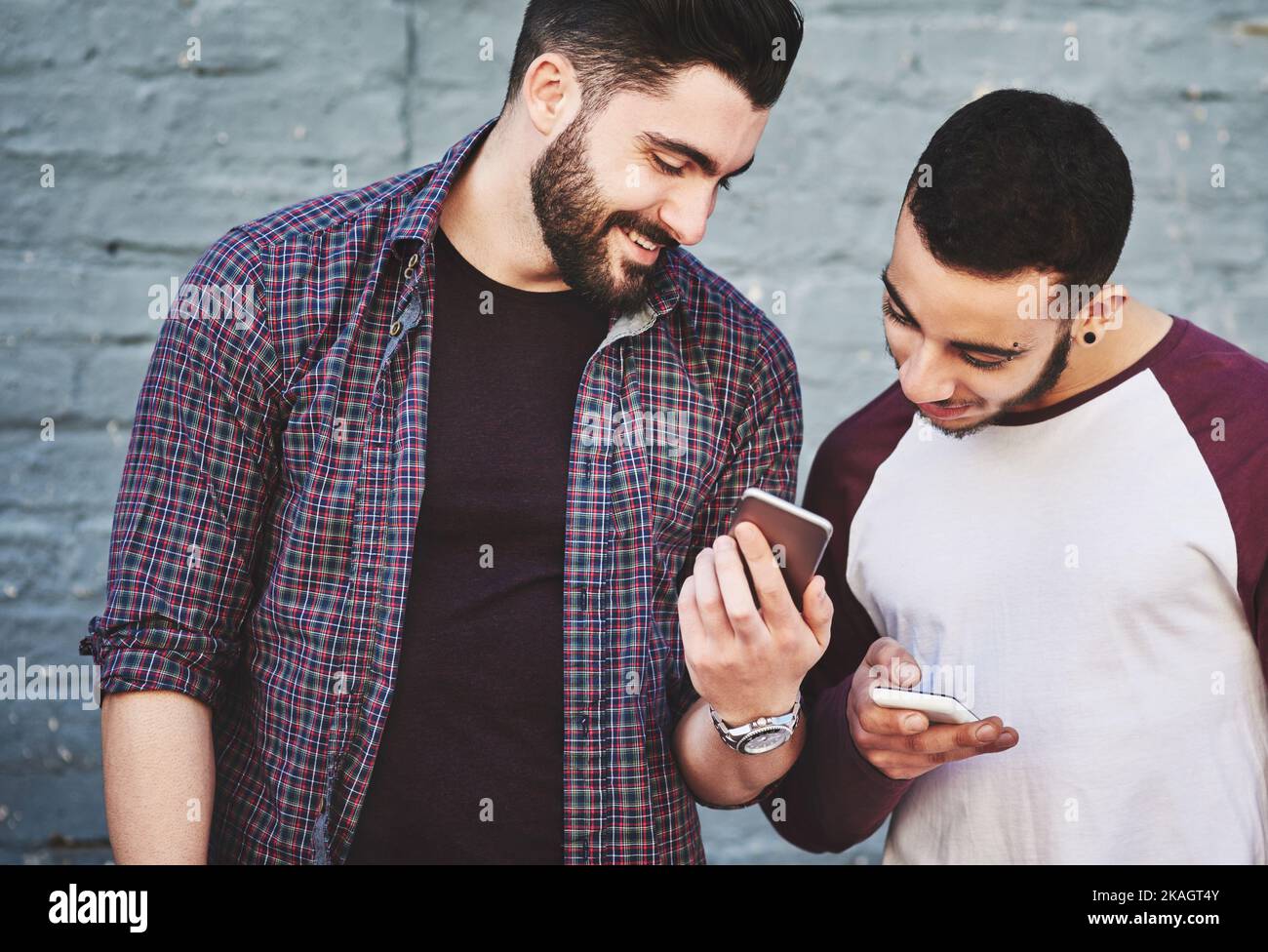 Remember this. two young men standing outdoors and using a mobile phone ...