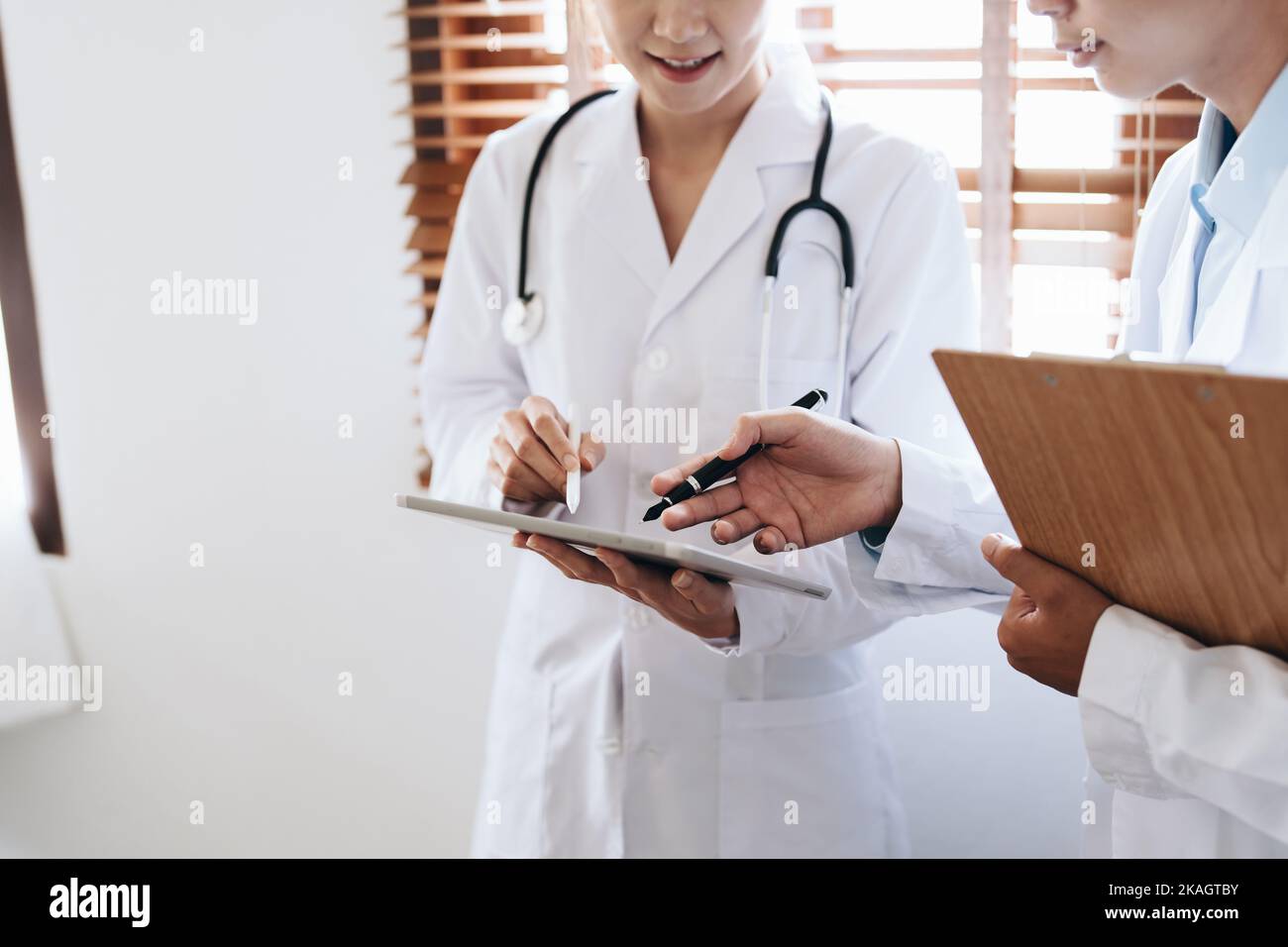 Portrait of an Asian female doctor and male doctor using a tablet to ...
