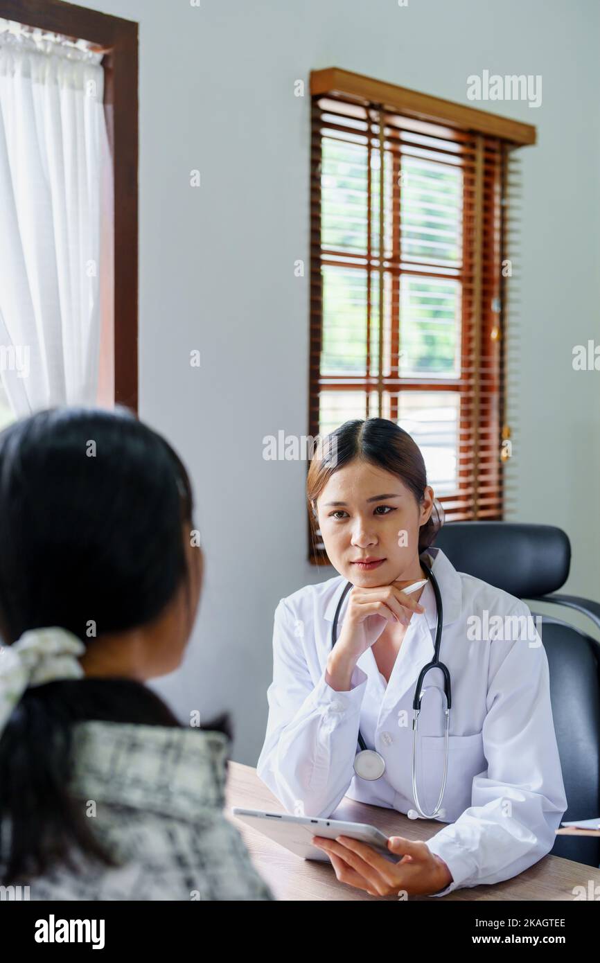 Portrait of a doctor advising clients on health issues holding a tablet ...