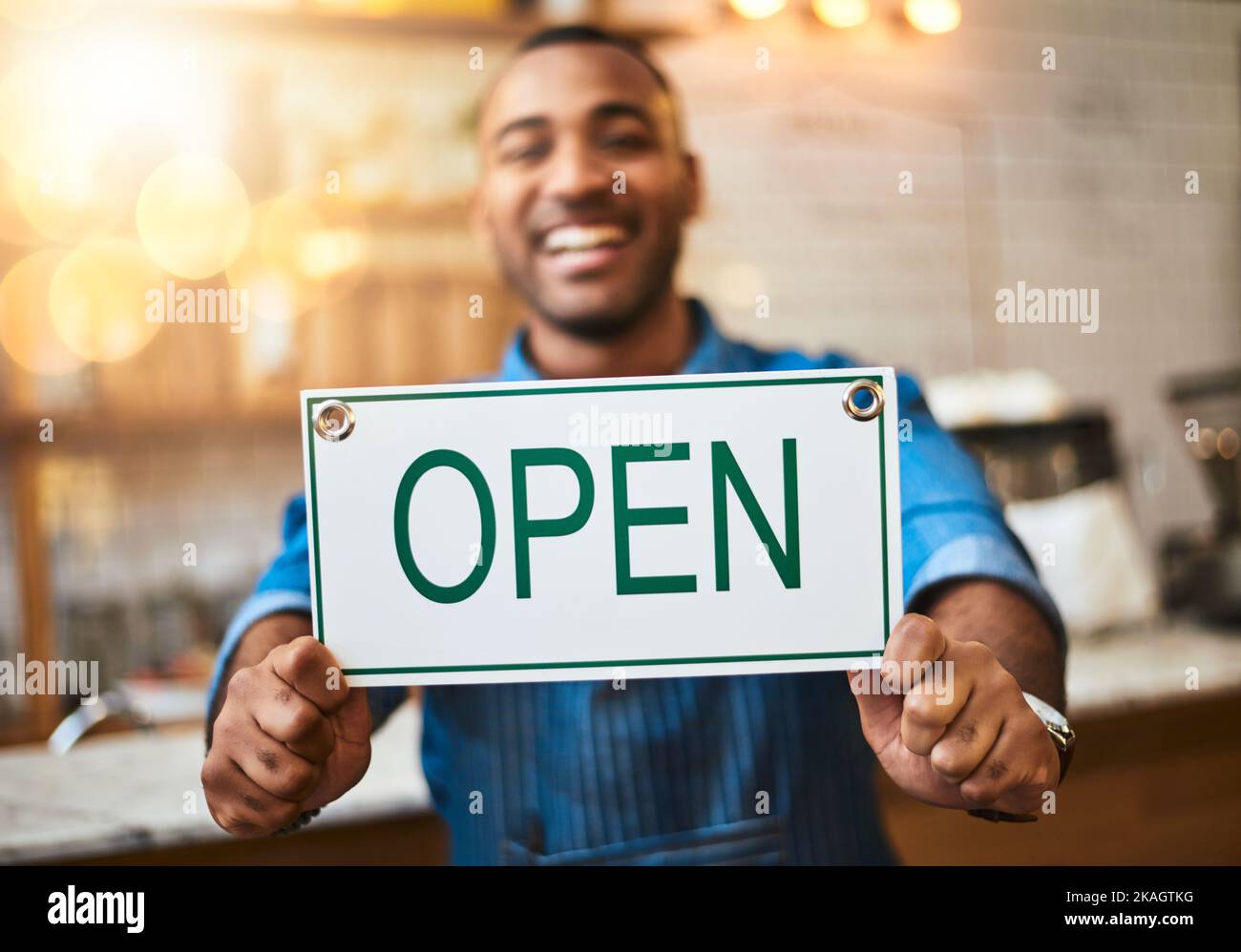 Our new store is now open. Portrait of a young man holding up an open ...
