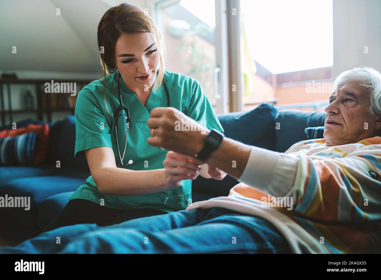 A young caregiver fastens a smart watch to the wrist of an elderly ...