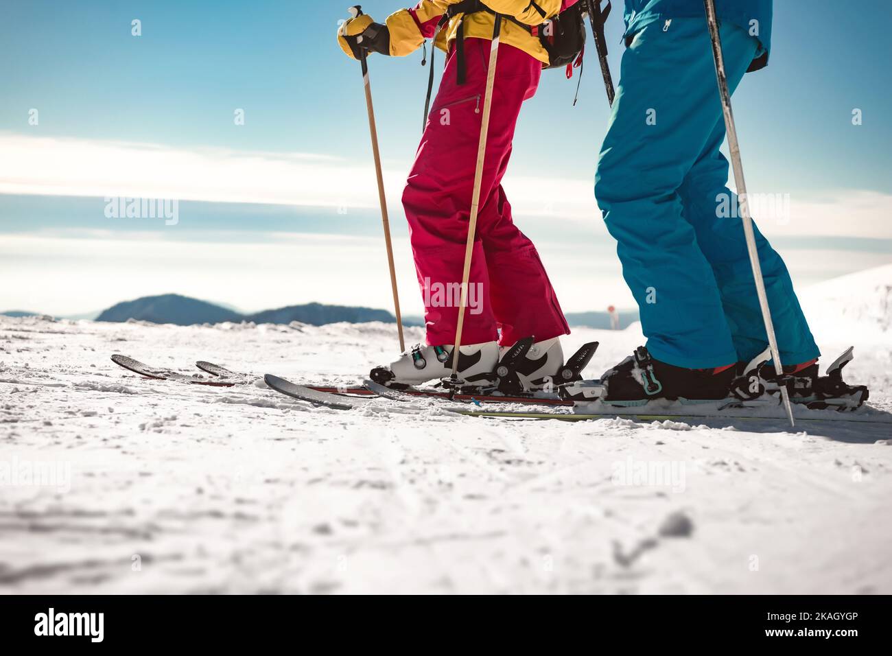 Close-up photo of legs. Two skiers male and female stands with ski ...