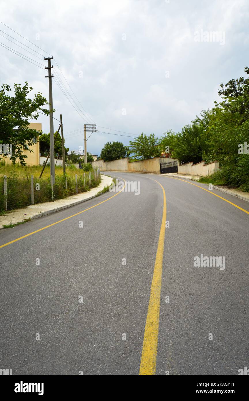 A quiet winding town road, clean and yellow lined asphalt road, winding ...