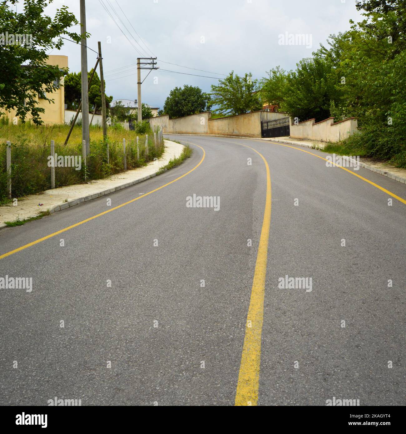 A quiet winding town road, clean and yellow lined asphalt road, winding ...