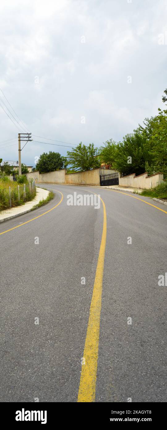 A quiet winding town road, clean and yellow lined asphalt road, winding ...