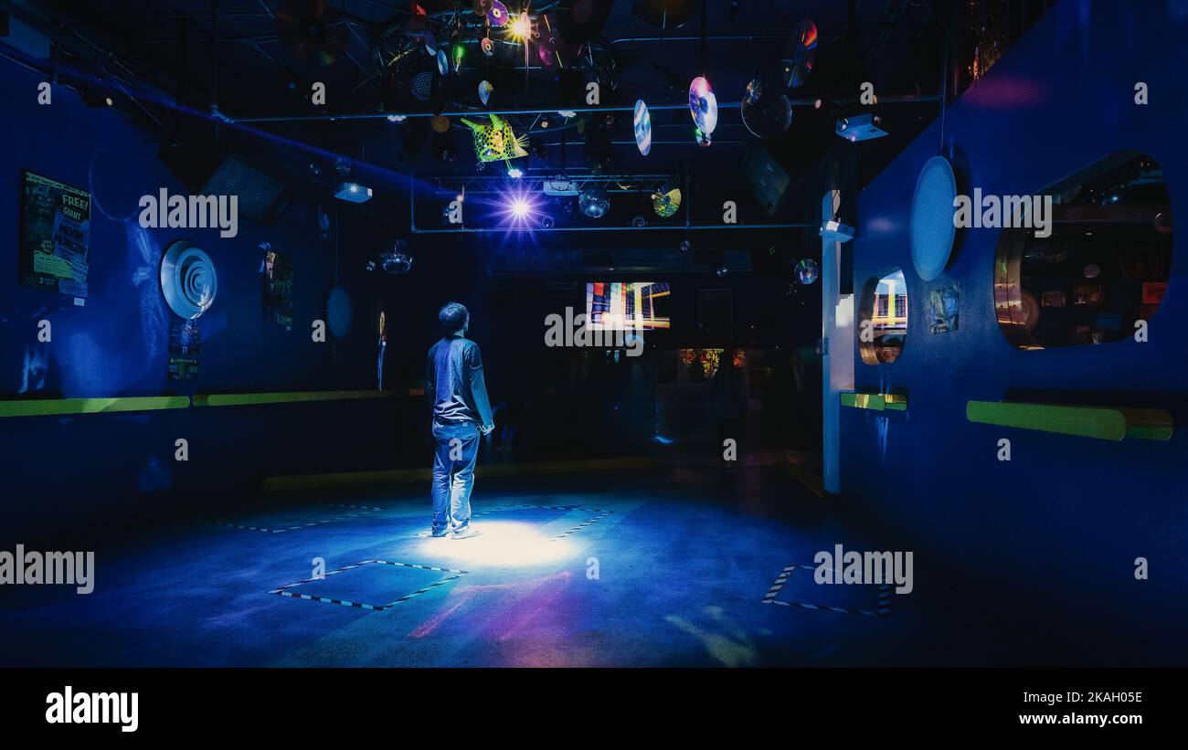 a young man stands alone on a dance floor with the spotlight on him ...