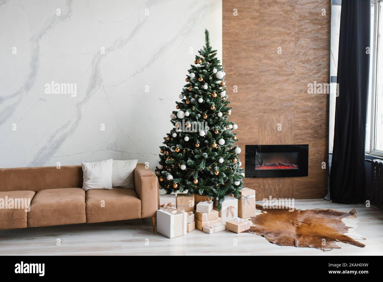 Beautiful Christmas tree with gifts near the modern fireplace and sofa ...