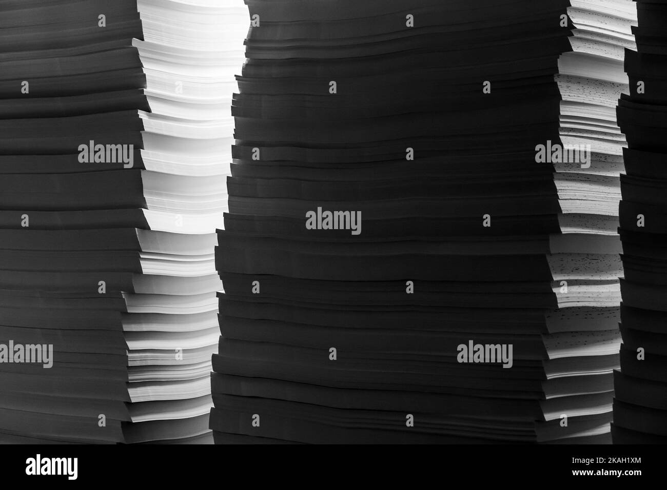 Piles of blank paper for printing illuminated with bright light in dark ...