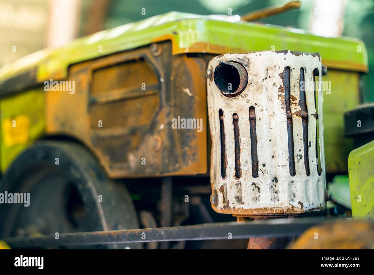 The muffler of the exhaust pipe of a walk-behind tractor against the ...
