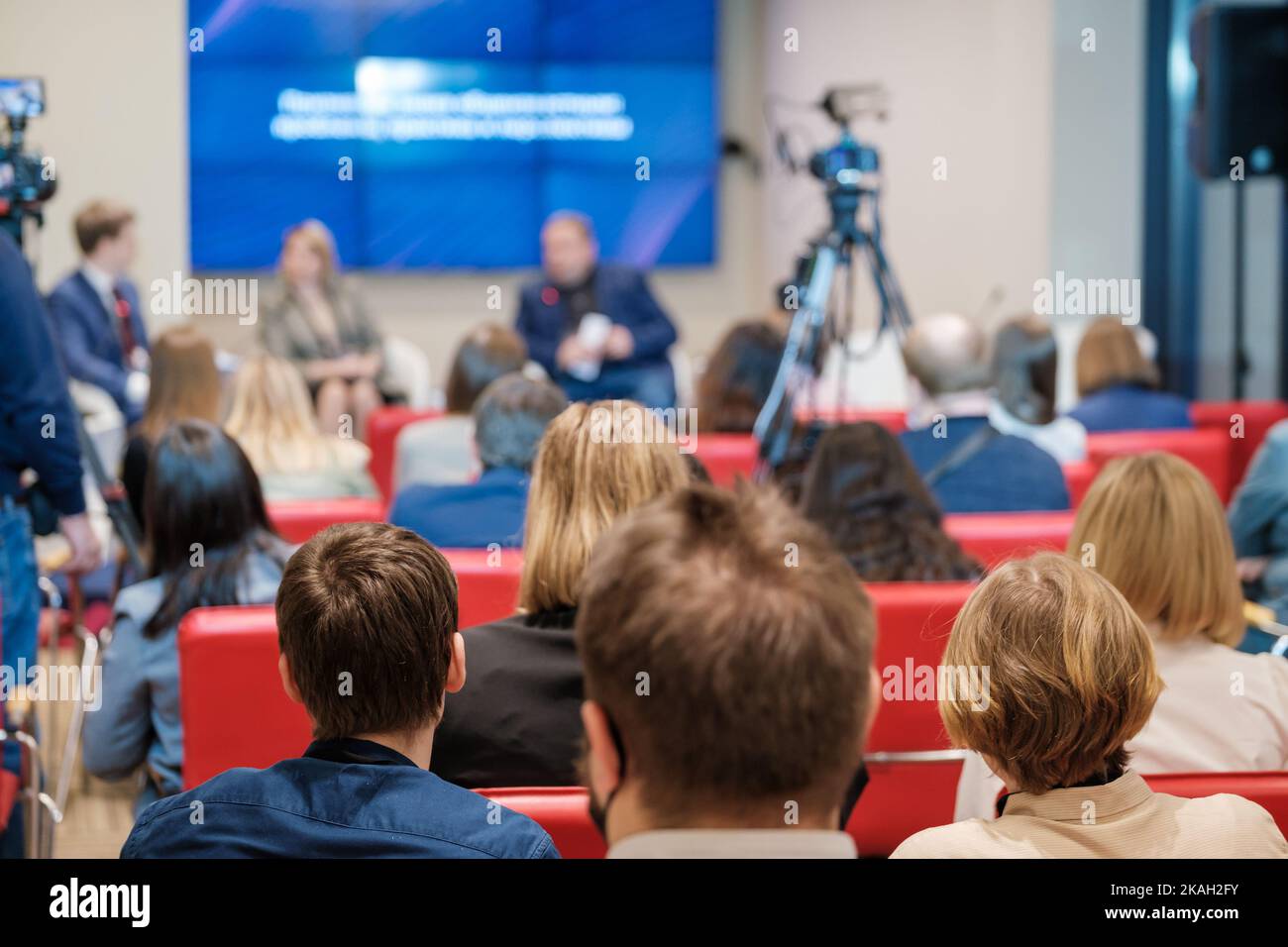 Anonymous people sitting on chairs in modern hall and listening to ...