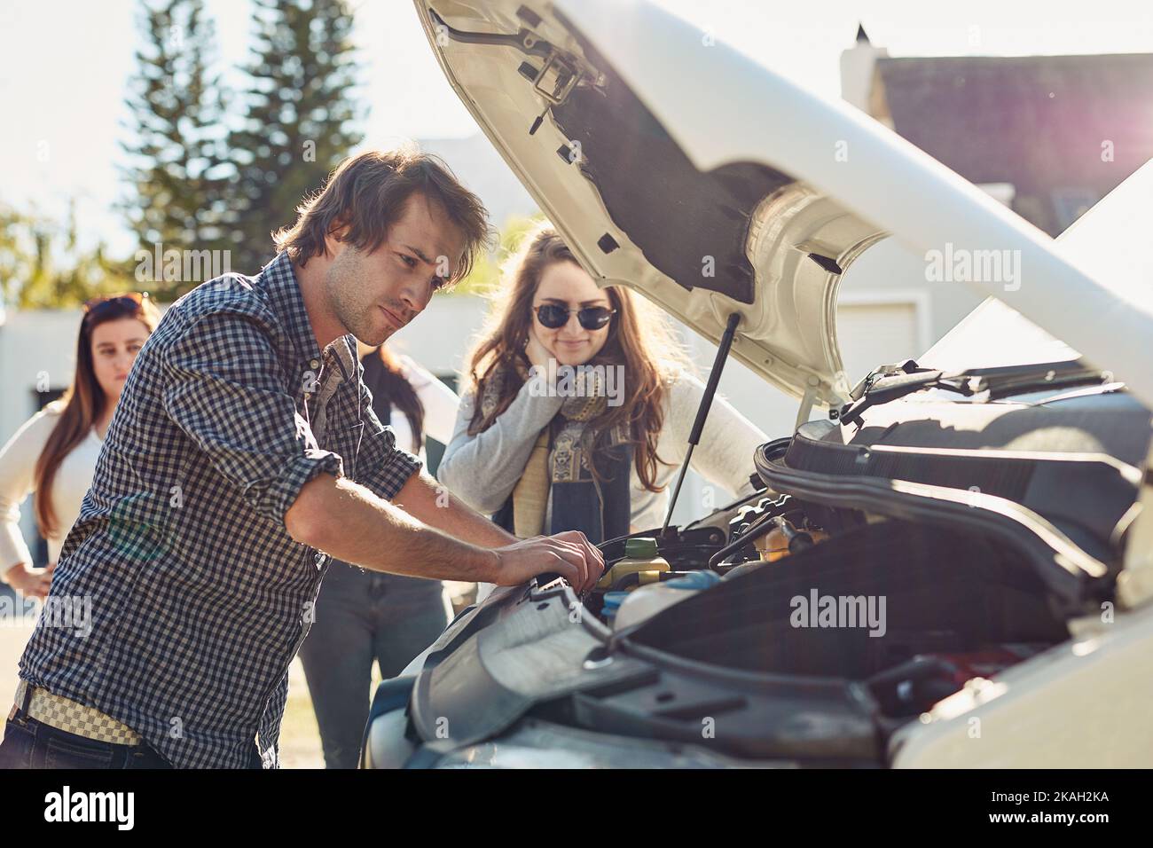 This is going to ruin our trip. a young man looking under the hood of a ...
