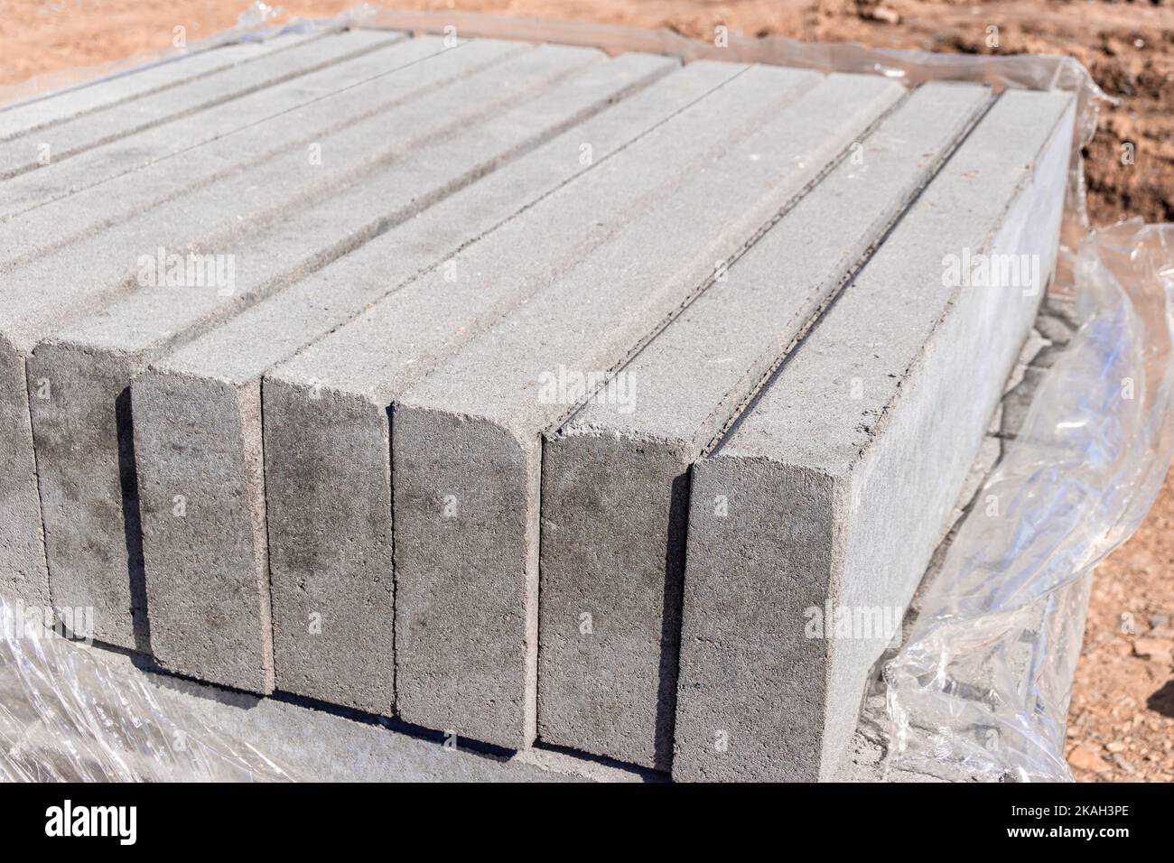 a new curbstone or curb unpacked stands in a pallet in several rows ...