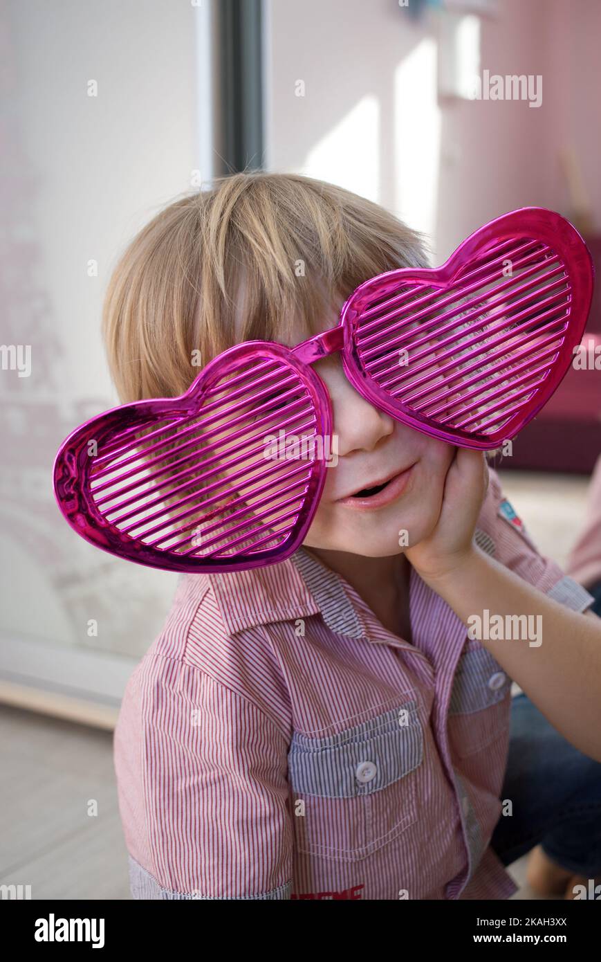 portrait of cute child boy in huge funny heart shaped glasses. Birthday ...