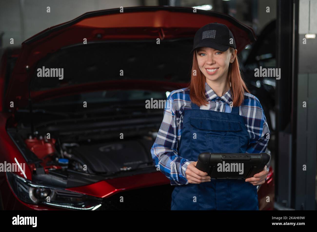 Caucasian female auto mechanic uses a special computer to diagnose ...
