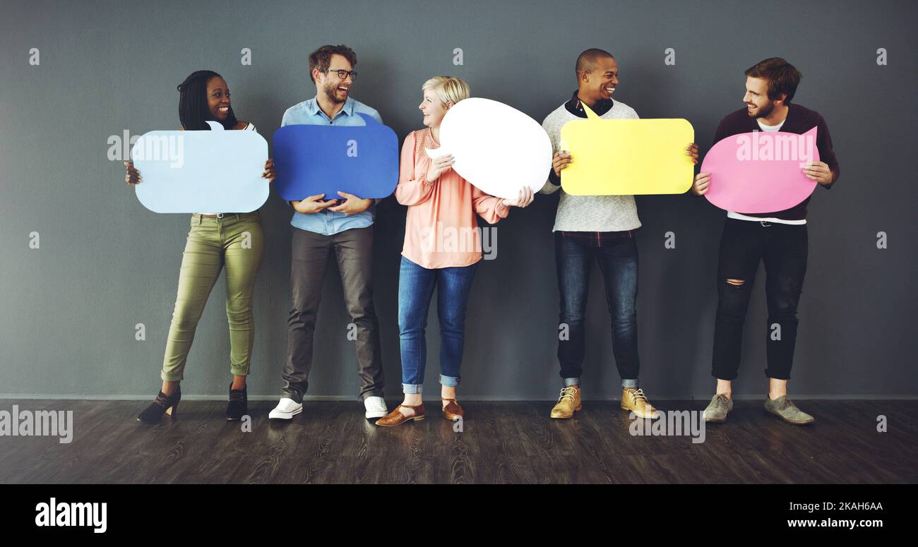 Talk it out. Studio shot of a diverse group of people holding up speech ...