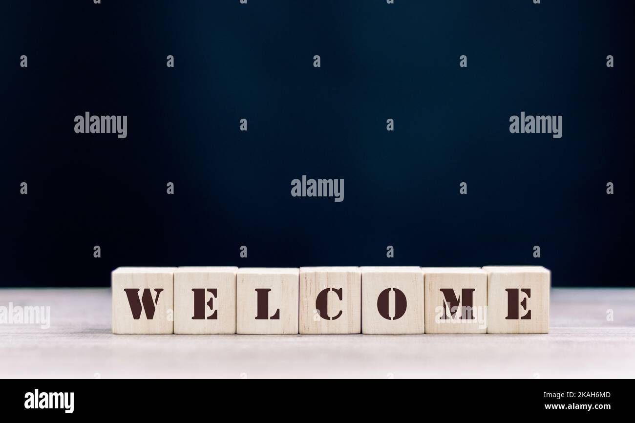 the word WELCOME is written on a wooden cubes structure. Cube on a ...