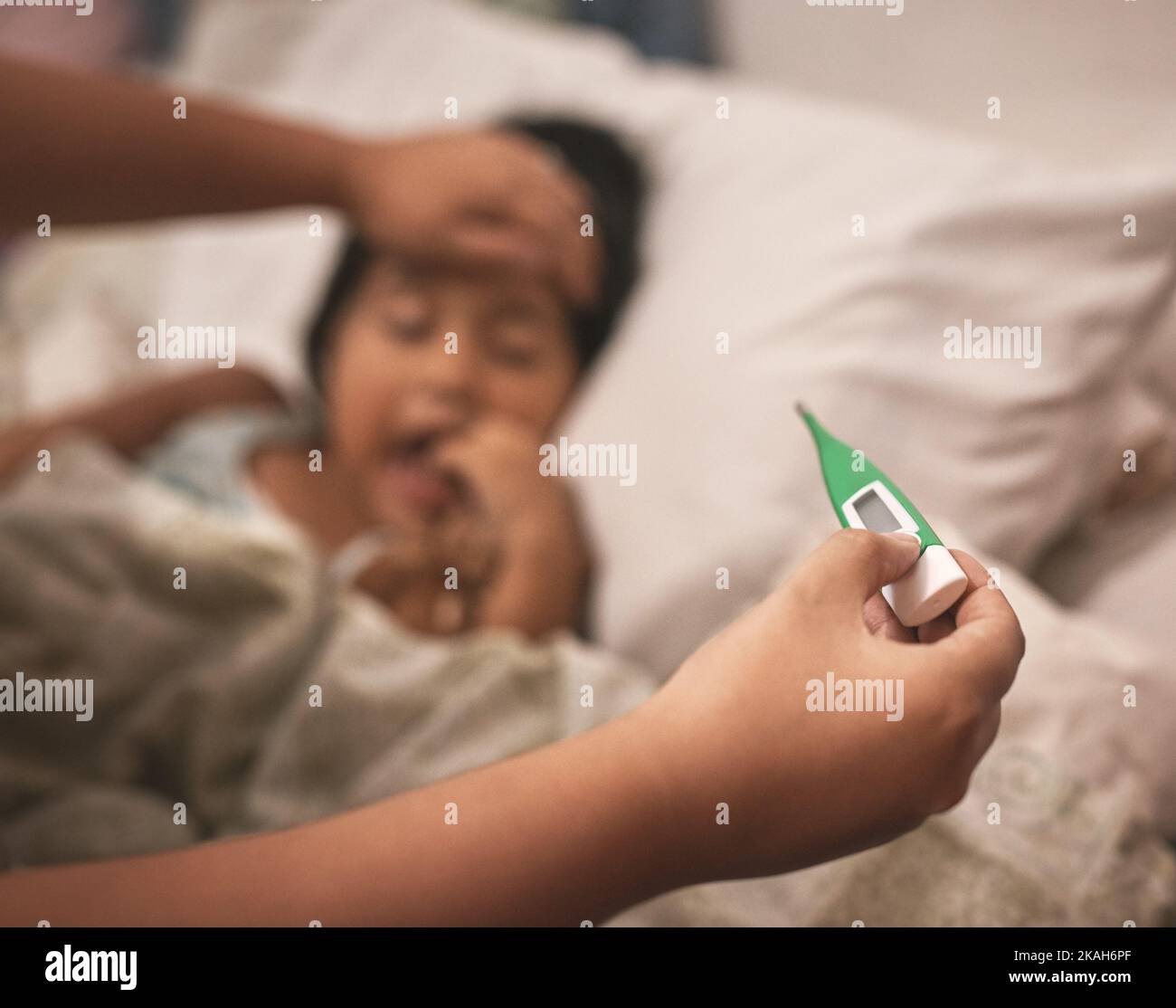 Lets check your temperature. a little girl lying in bed while her ...