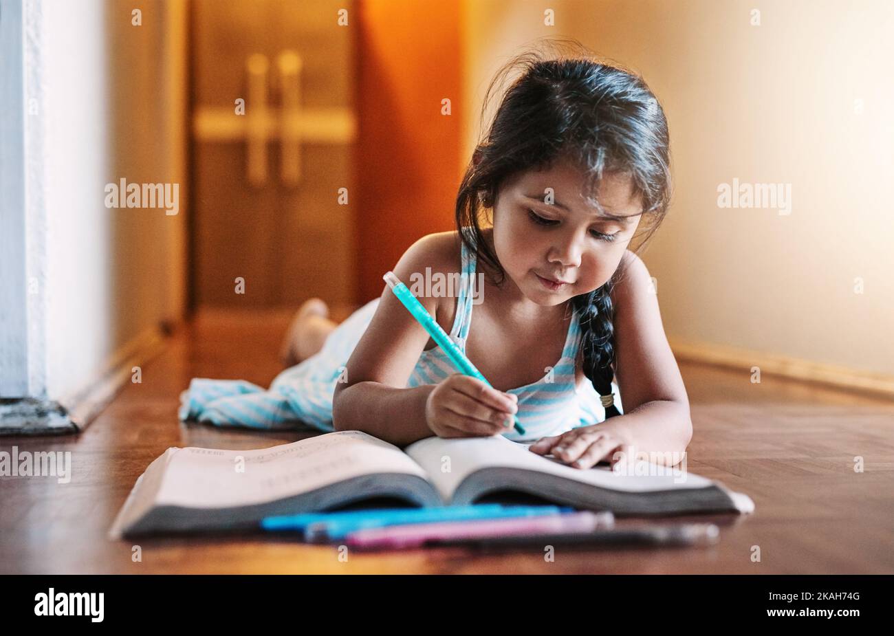 Doing homework like a good girl. a focused little girl writing inside ...