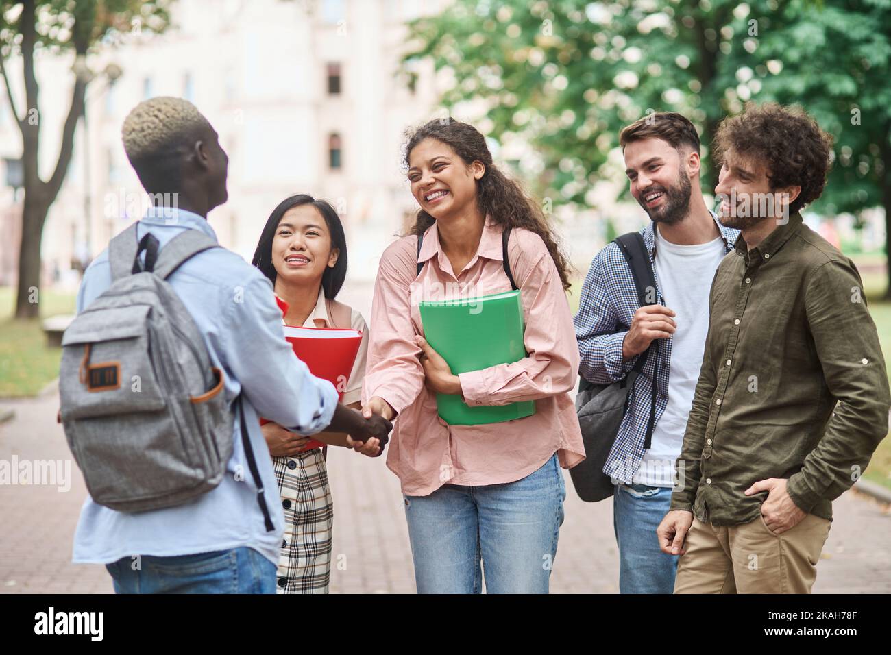 group of students meeting their friend with a handshake Stock Photo - Alamy