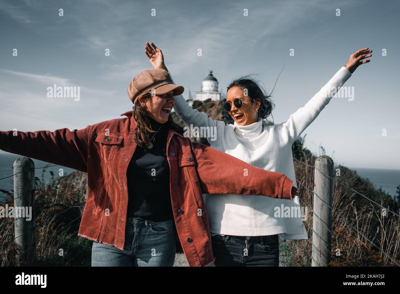 two caucasian brunette girls come from the lighthouse running happy and ...