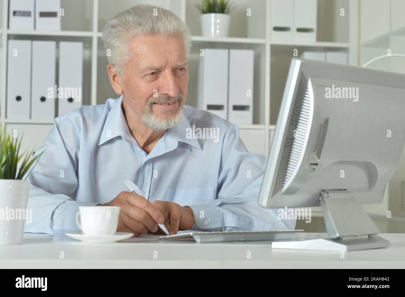 Elderly man sits with a computer in the office Stock Photo - Alamy