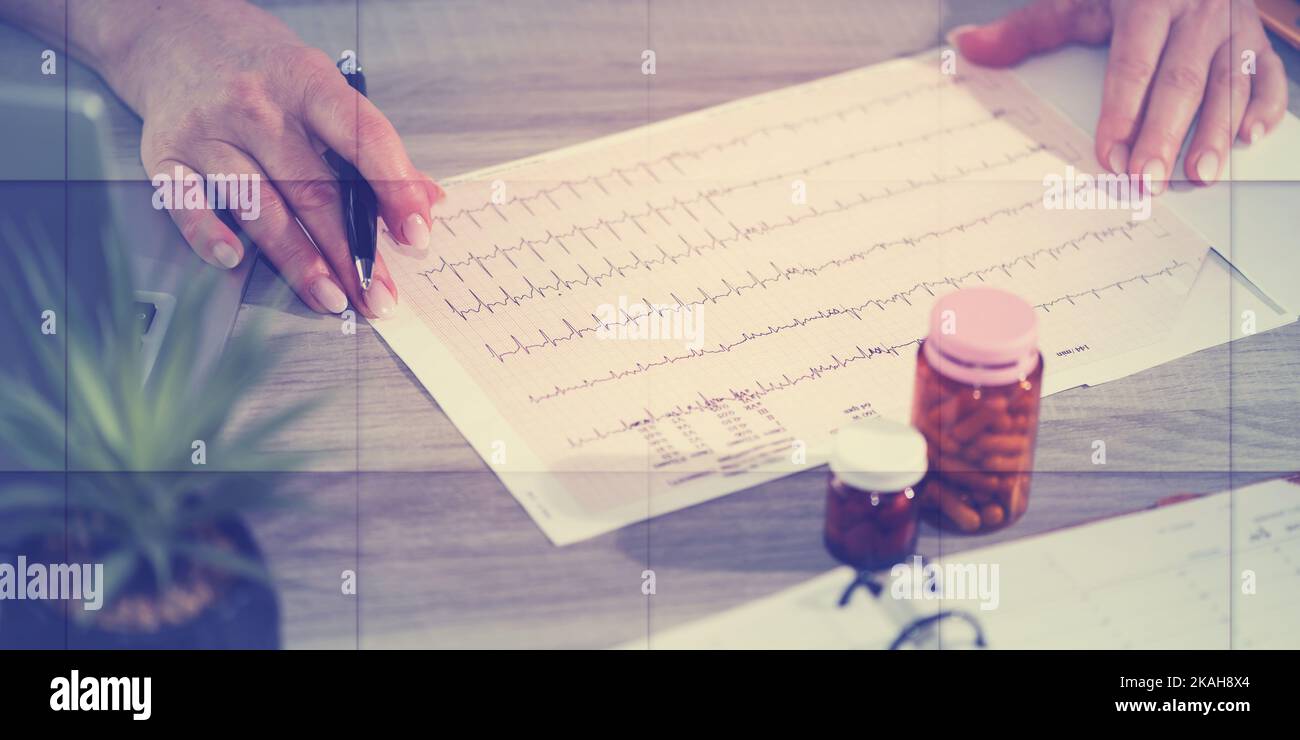 Female cardiologist examining an ecg graph in medical office, geometric ...