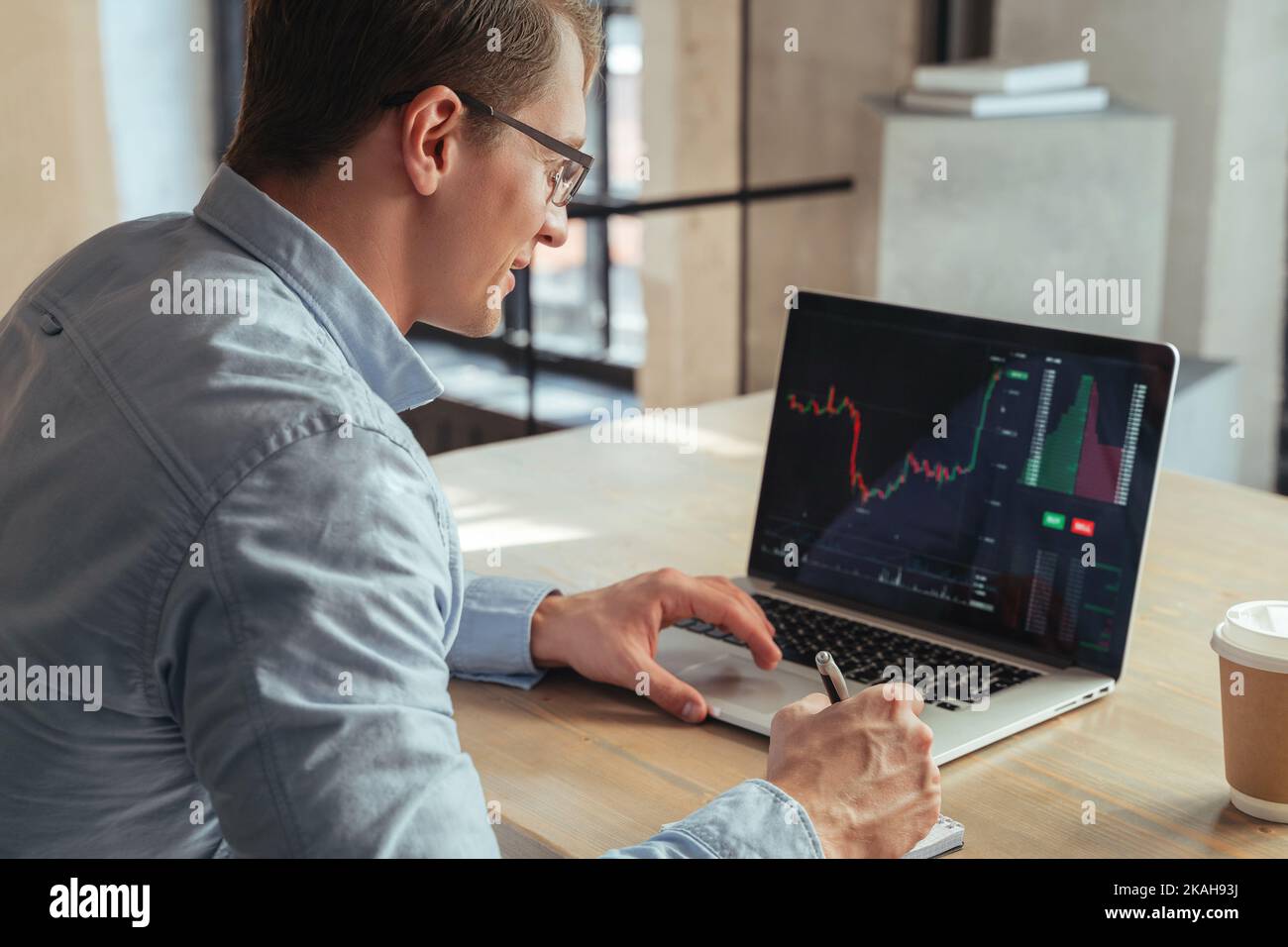 Smiling financial analyst making notes analyzing crypto currency market ...