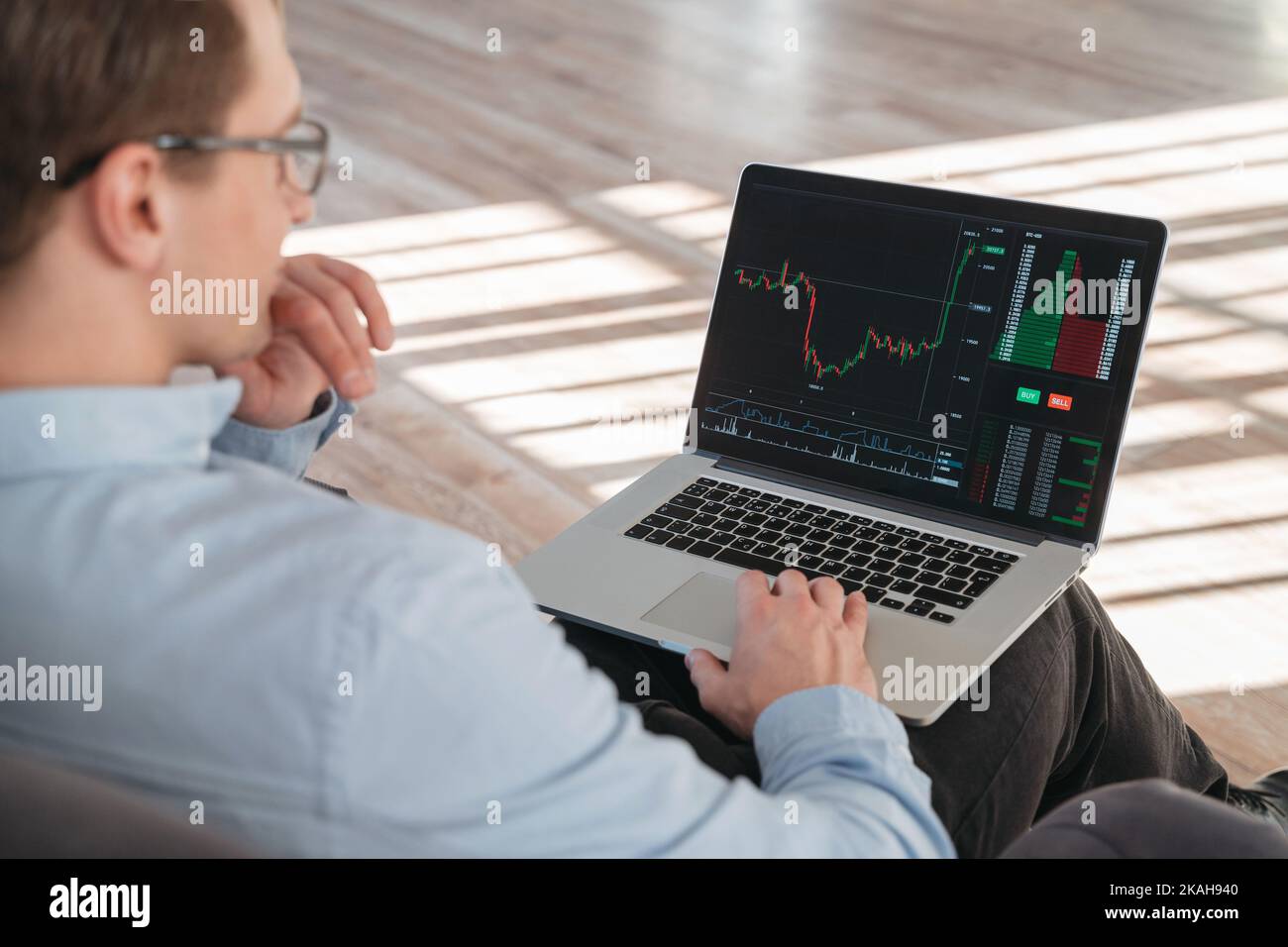 Close up shot of trade investor sitting with laptop on knees, analyzing ...