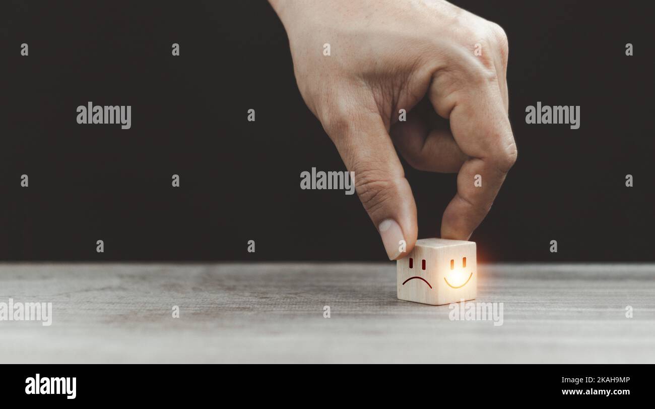 Close up customer hand choose smiley face and sad face icon on wood ...