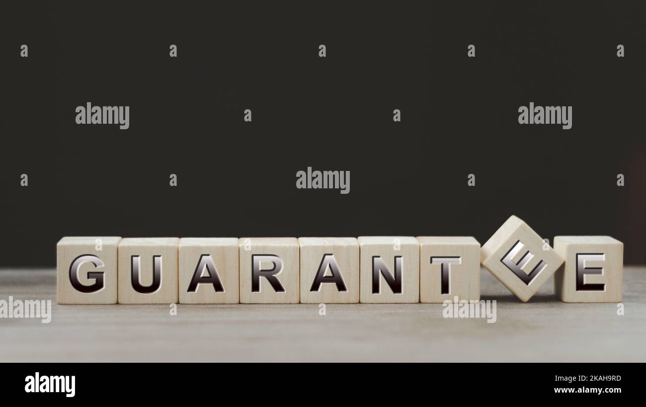 Text GUARANTEE on wood cube block, stock investment concept. The text ...