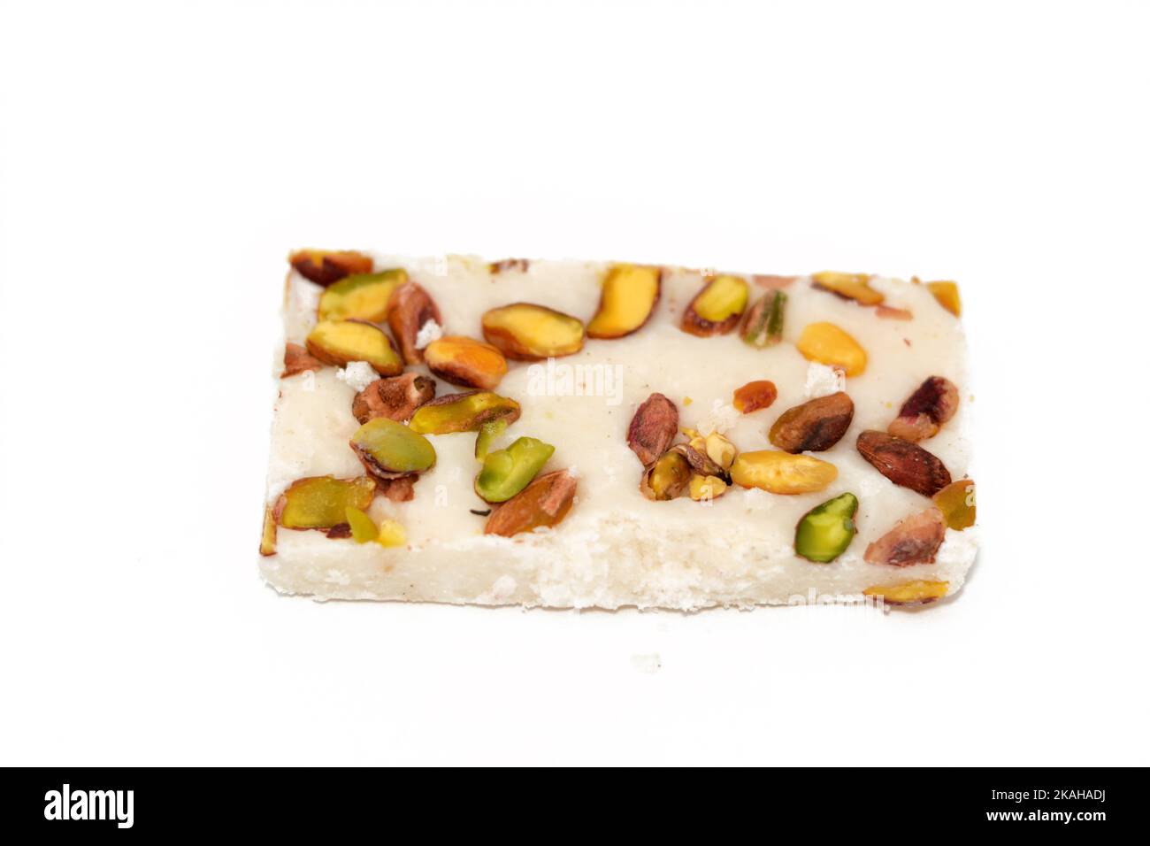 A piece of soft coconut Egyptian candy covered with pistachios ...