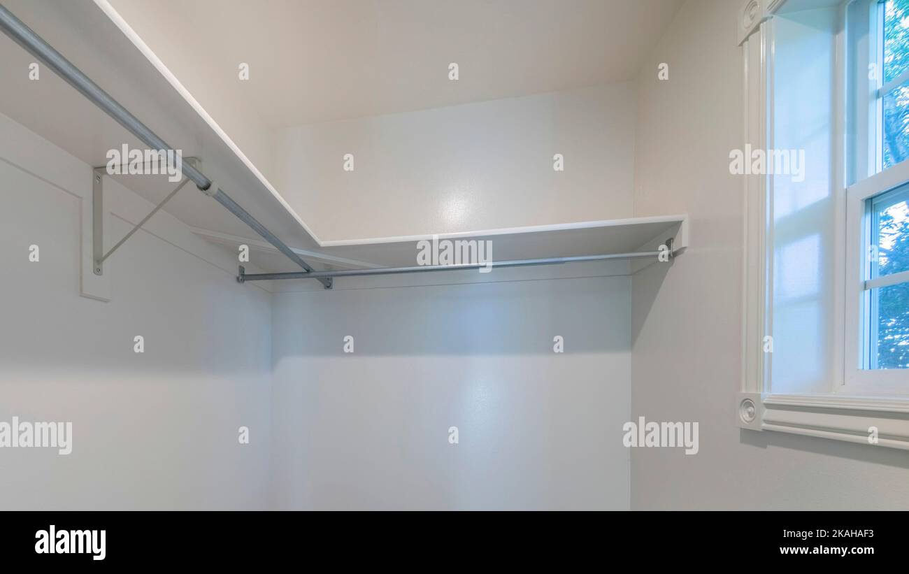 Panorama Small empty walk in closet with white interior and window ...