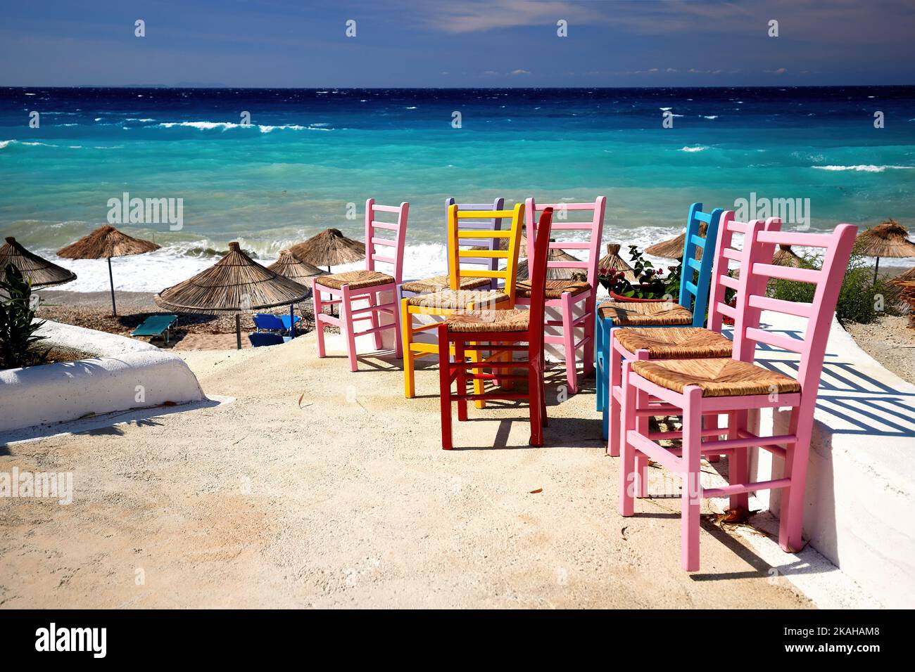 Multicoloured chairs against the backdrop of the green-blue sea and the ...
