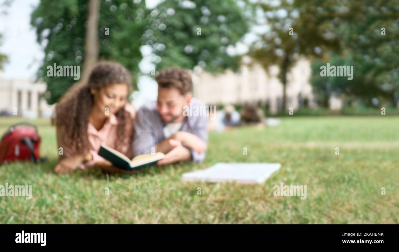 blurry image of students reading a textbook lying on the grass Stock ...