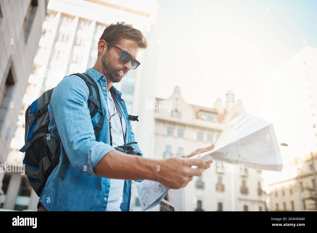 Travel is an investment in yourself. a young man looking at a map while ...