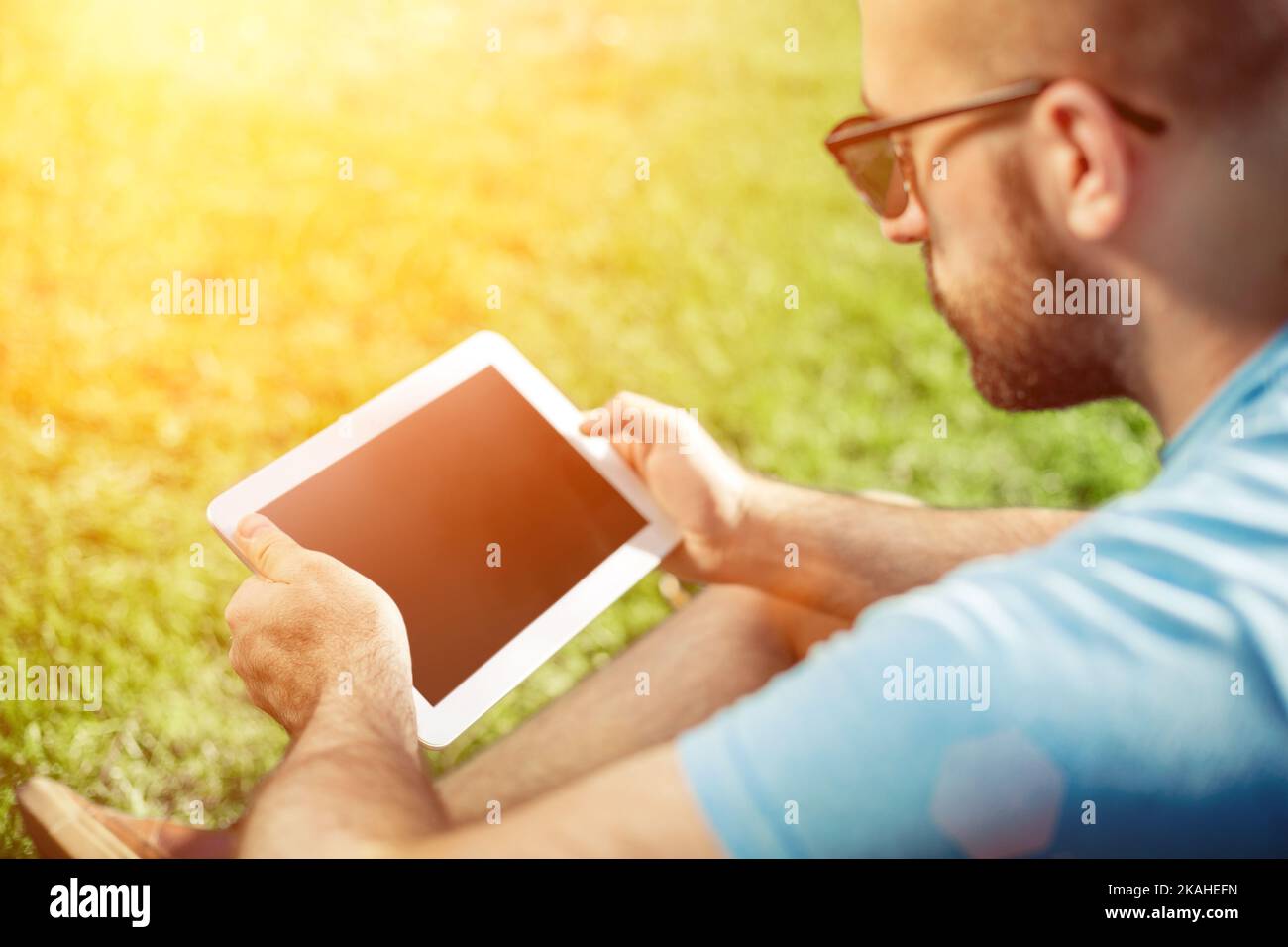 Young man using and typing tablet computer in summer grass Stock Photo ...