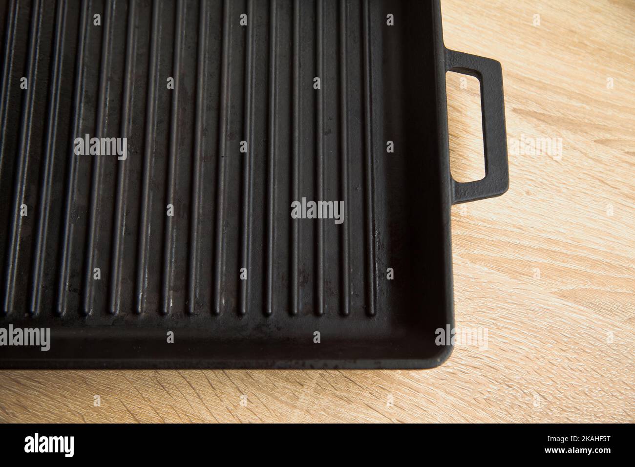 Empty black cast heavy iron grill pan on modern oak kitchen countertop ...